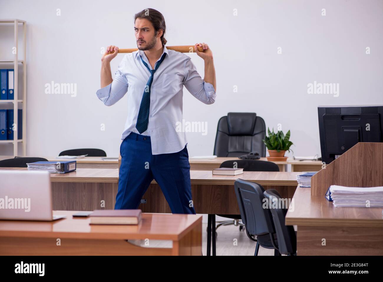 Young furious employee holding baseball bat in the office Stock Photo ...
