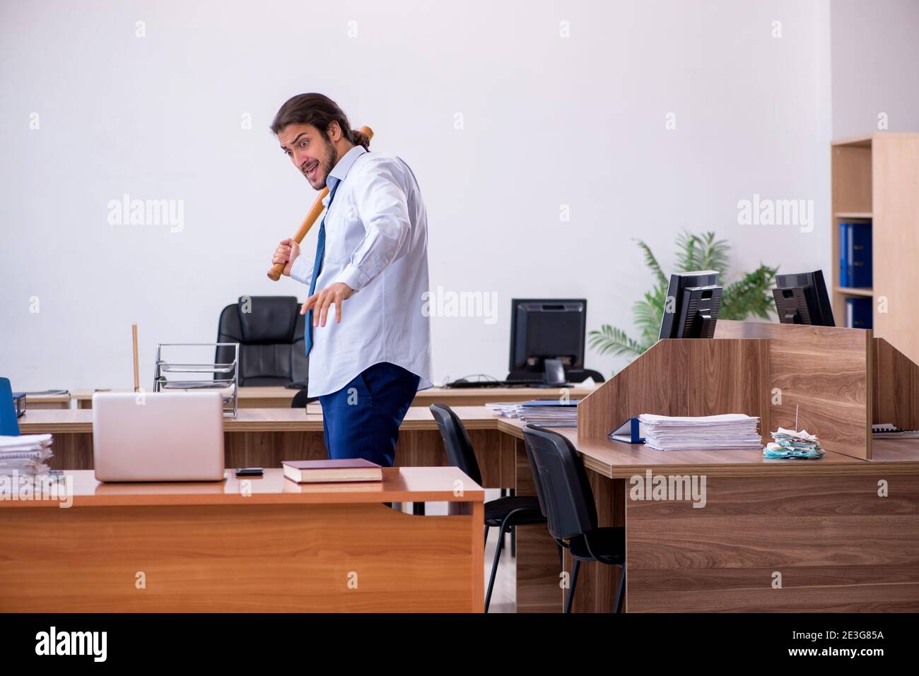 Young furious employee holding baseball bat in the office Stock Photo ...