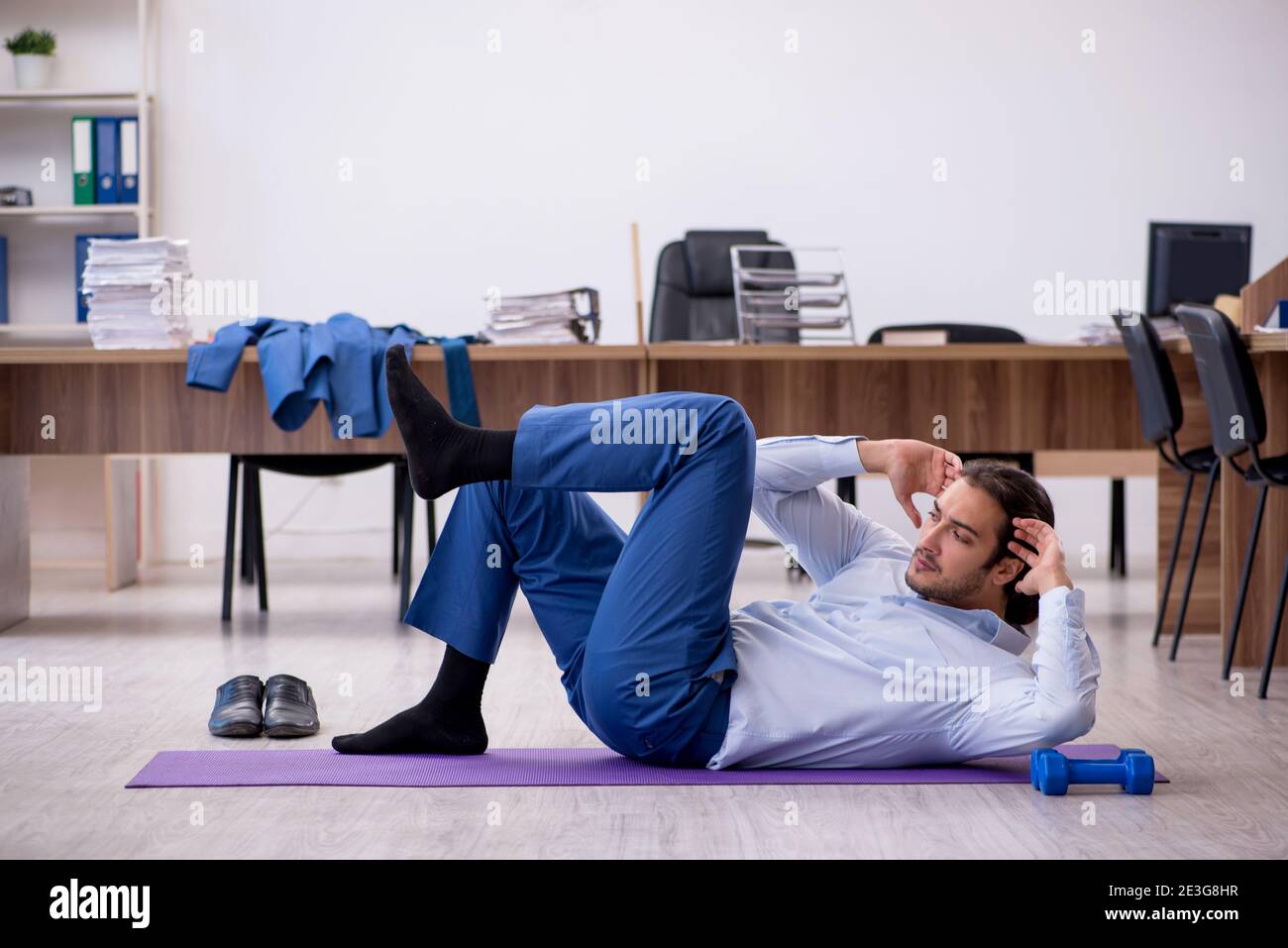 Young employee doing sport exercises during break Stock Photo - Alamy