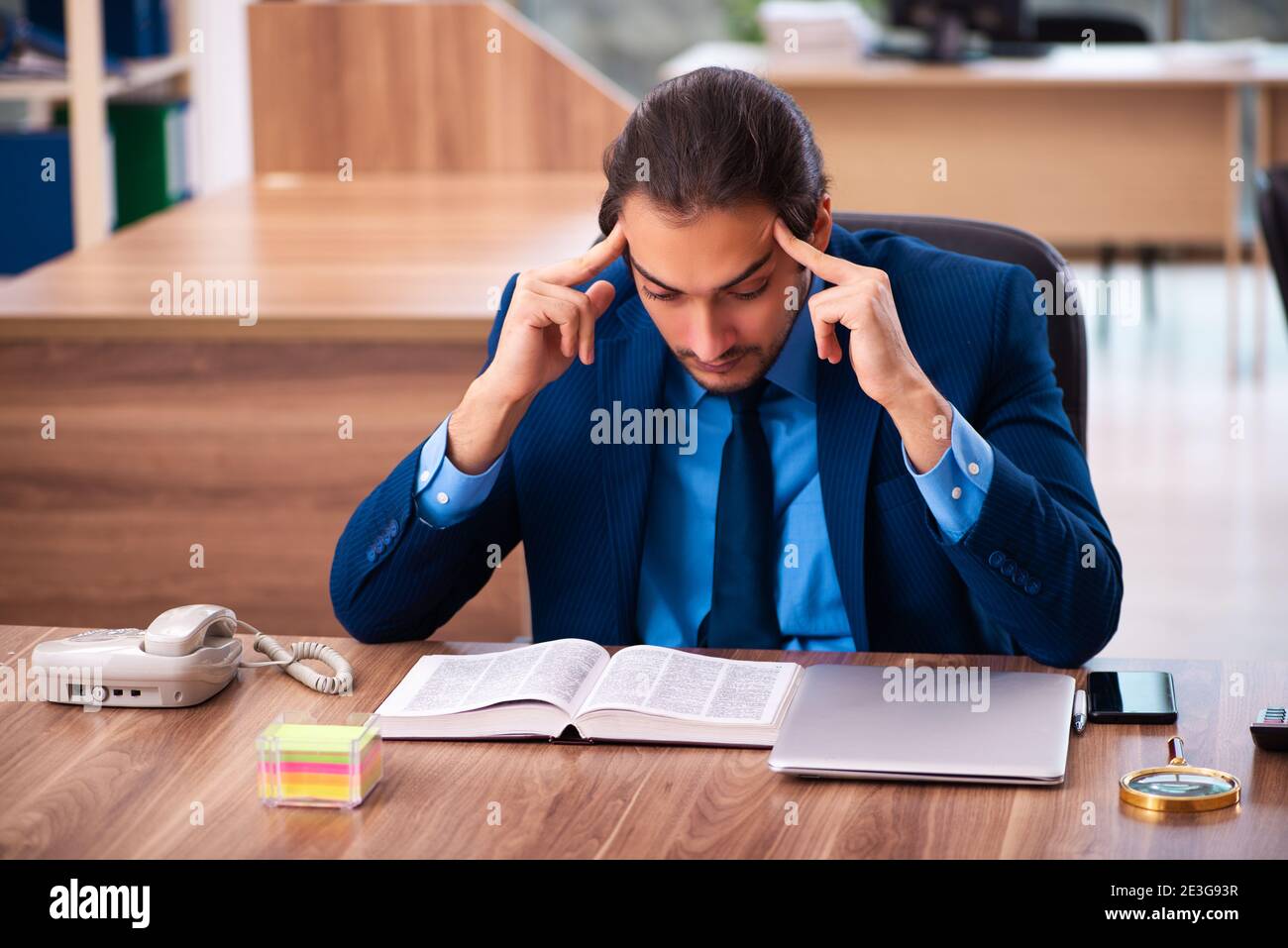 Young employee reading book in the office Stock Photo - Alamy