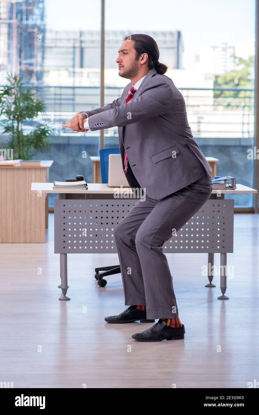 Young employee doing sport exercises at workplace Stock Photo - Alamy