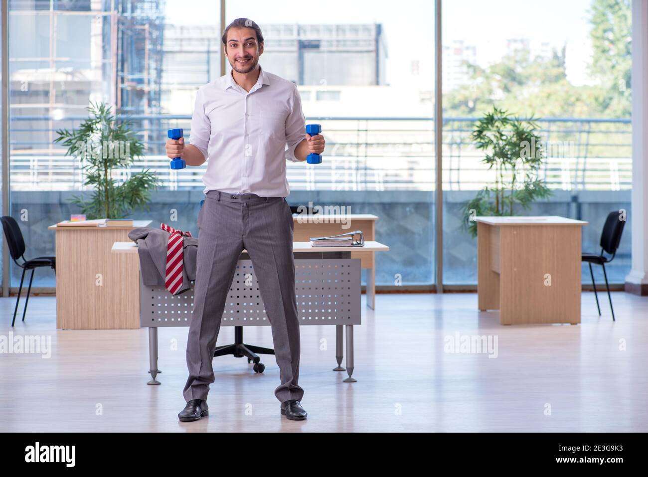 Young employee doing sport exercises at workplace Stock Photo - Alamy