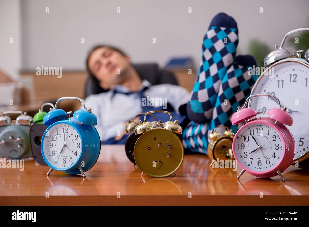 Young businessman sleeping in the office in time management concept ...