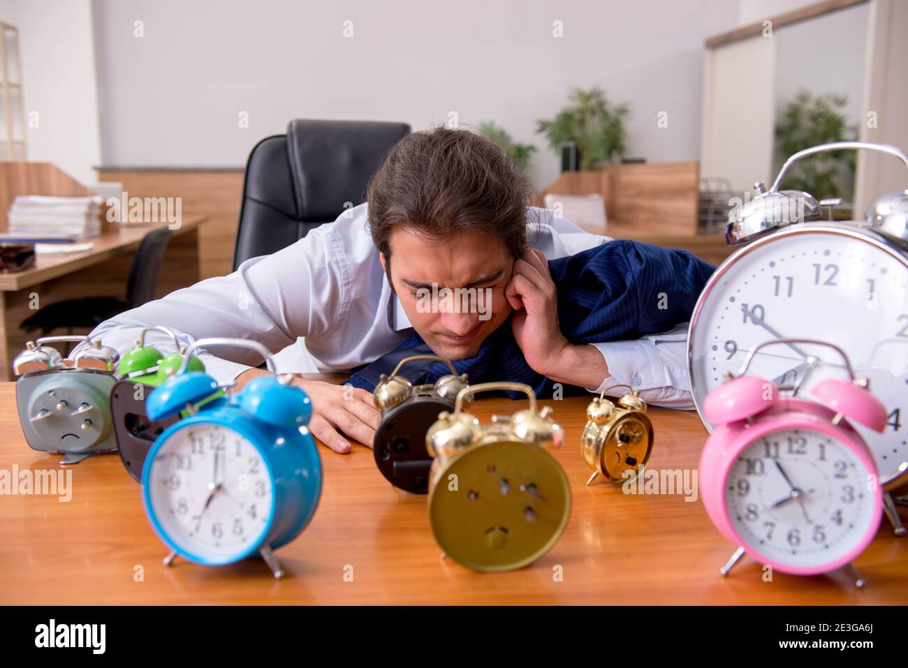 Young businessman sleeping in the office in time management concept ...