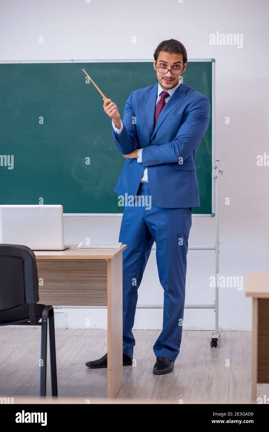 Young teacher in suit in front of green board Stock Photo - Alamy