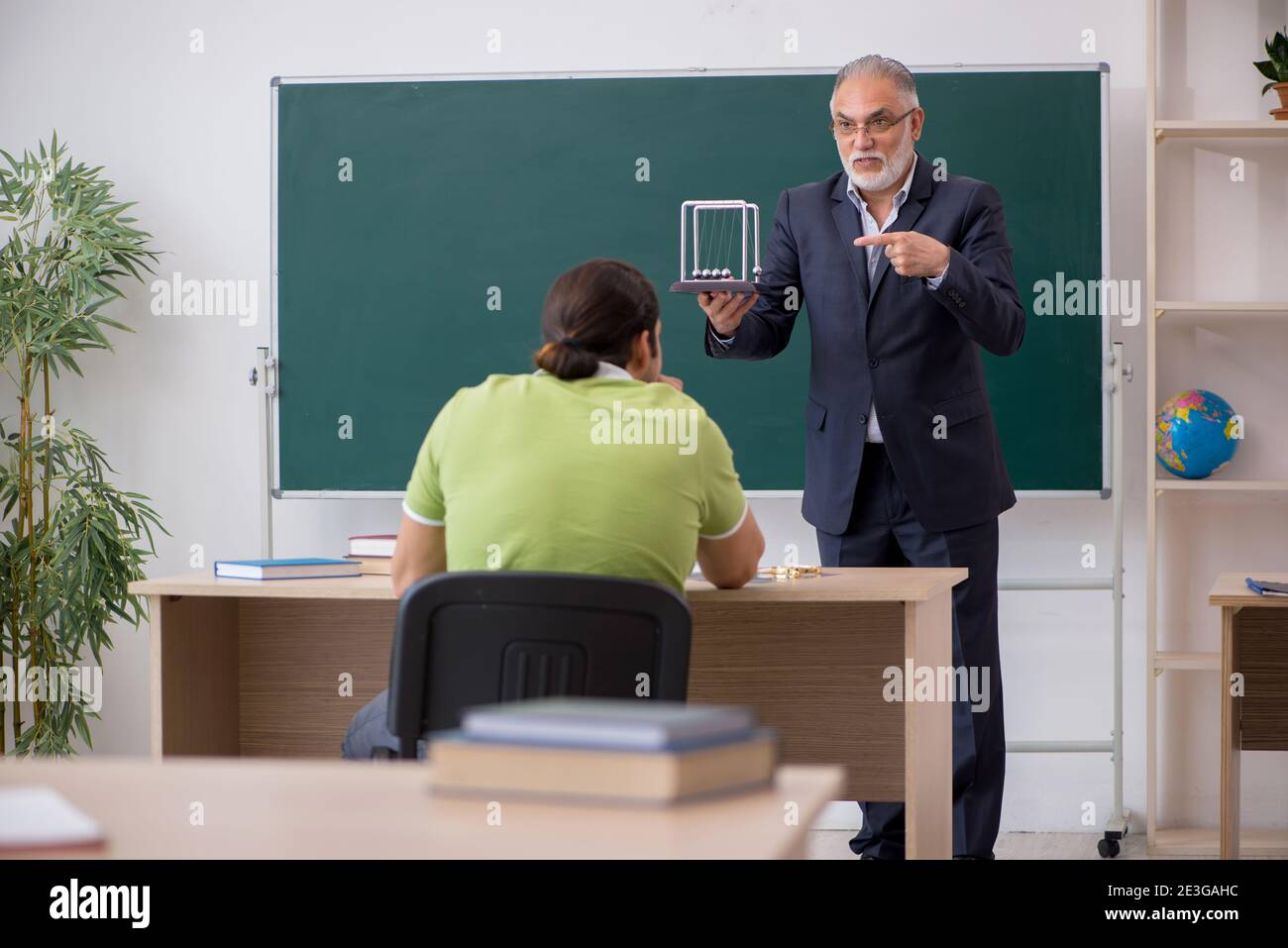 Aged physics teacher and young student in the classroom Stock Photo - Alamy