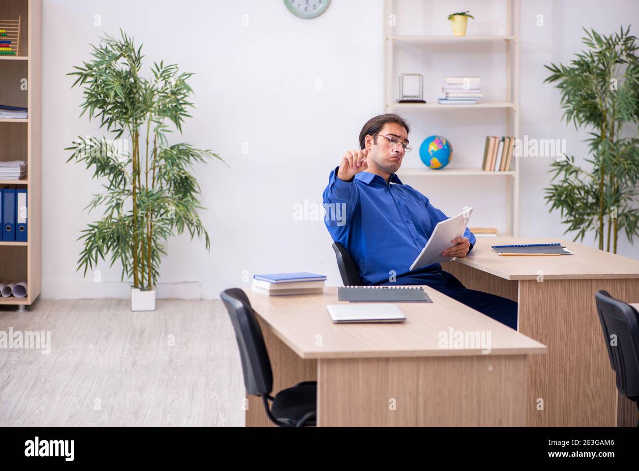 Young teacher checking notes in the classroom Stock Photo - Alamy