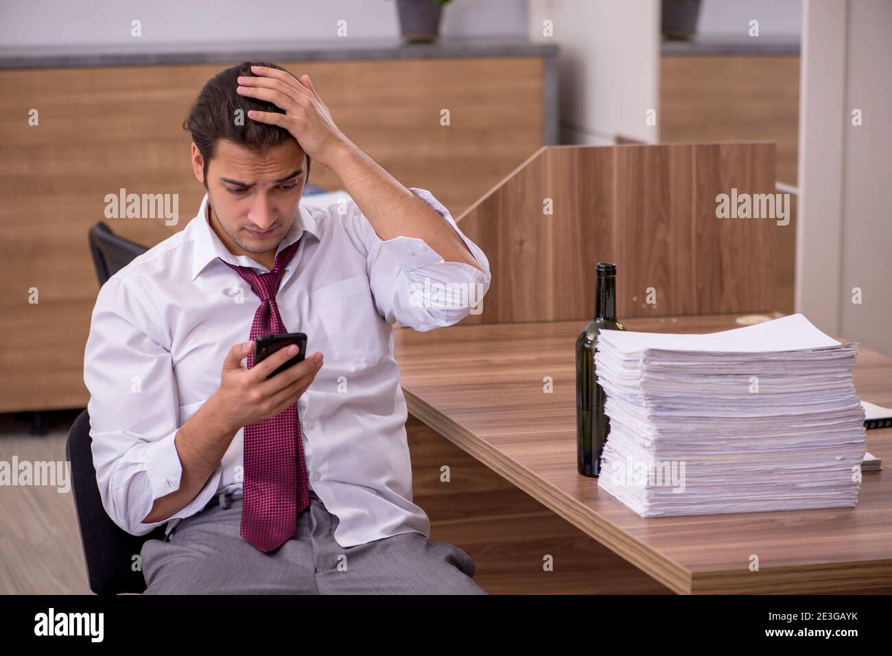 Young employee drinking alcohol in the office Stock Photo - Alamy