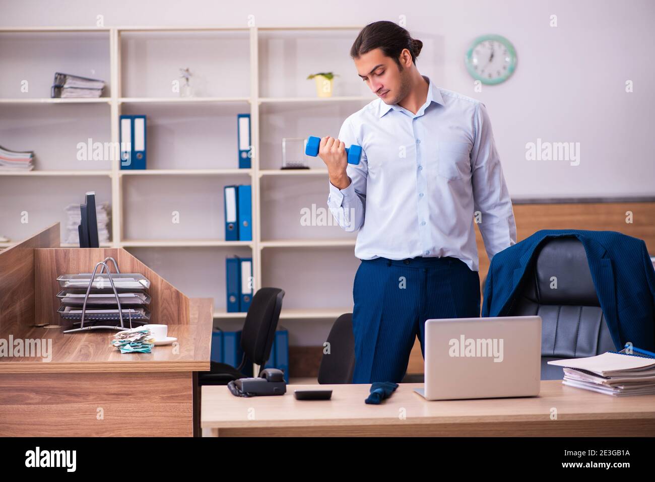 Young employee doing physical exercises at workplace Stock Photo - Alamy