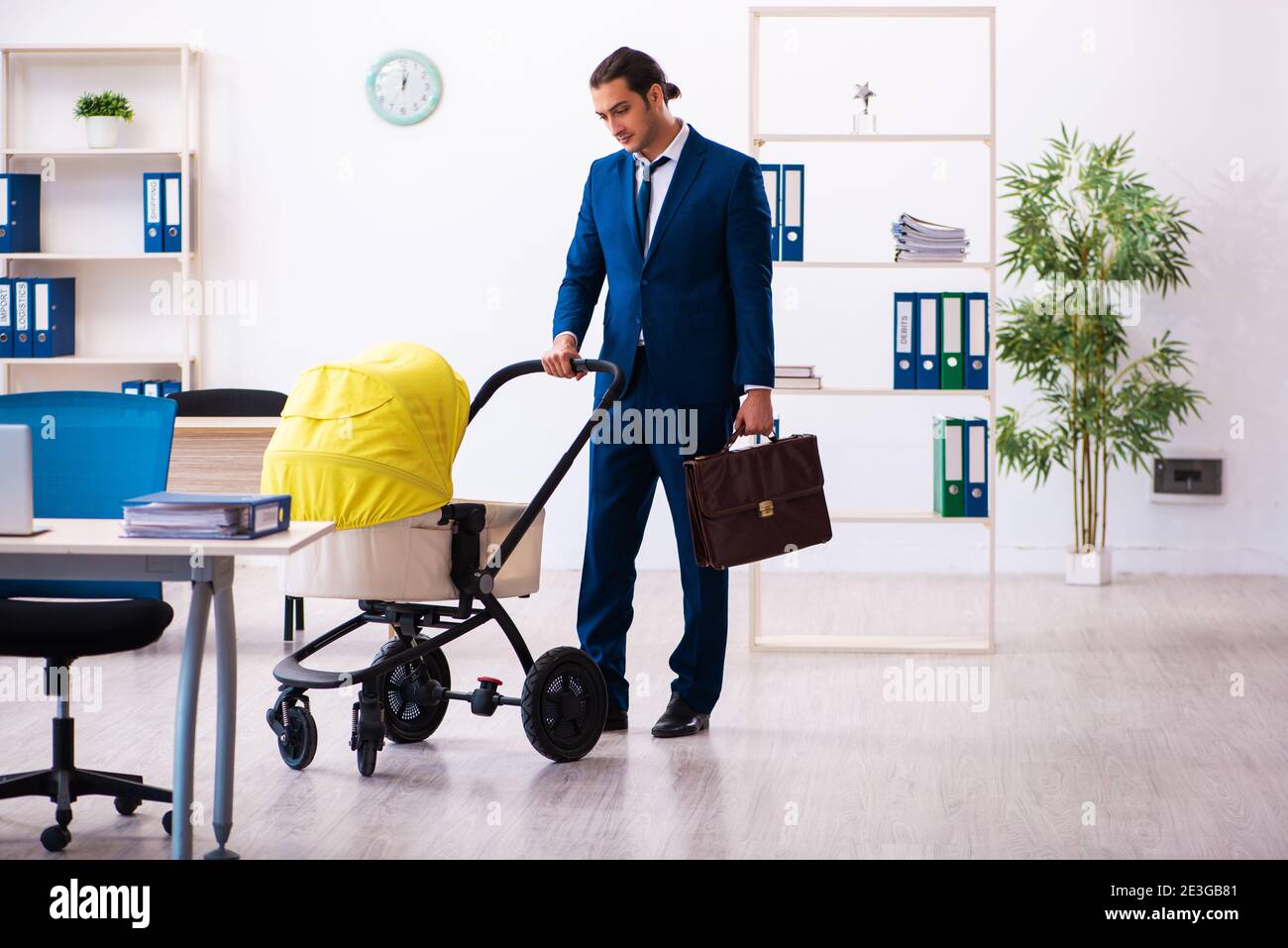 Young employee looking after kid at workplace Stock Photo - Alamy
