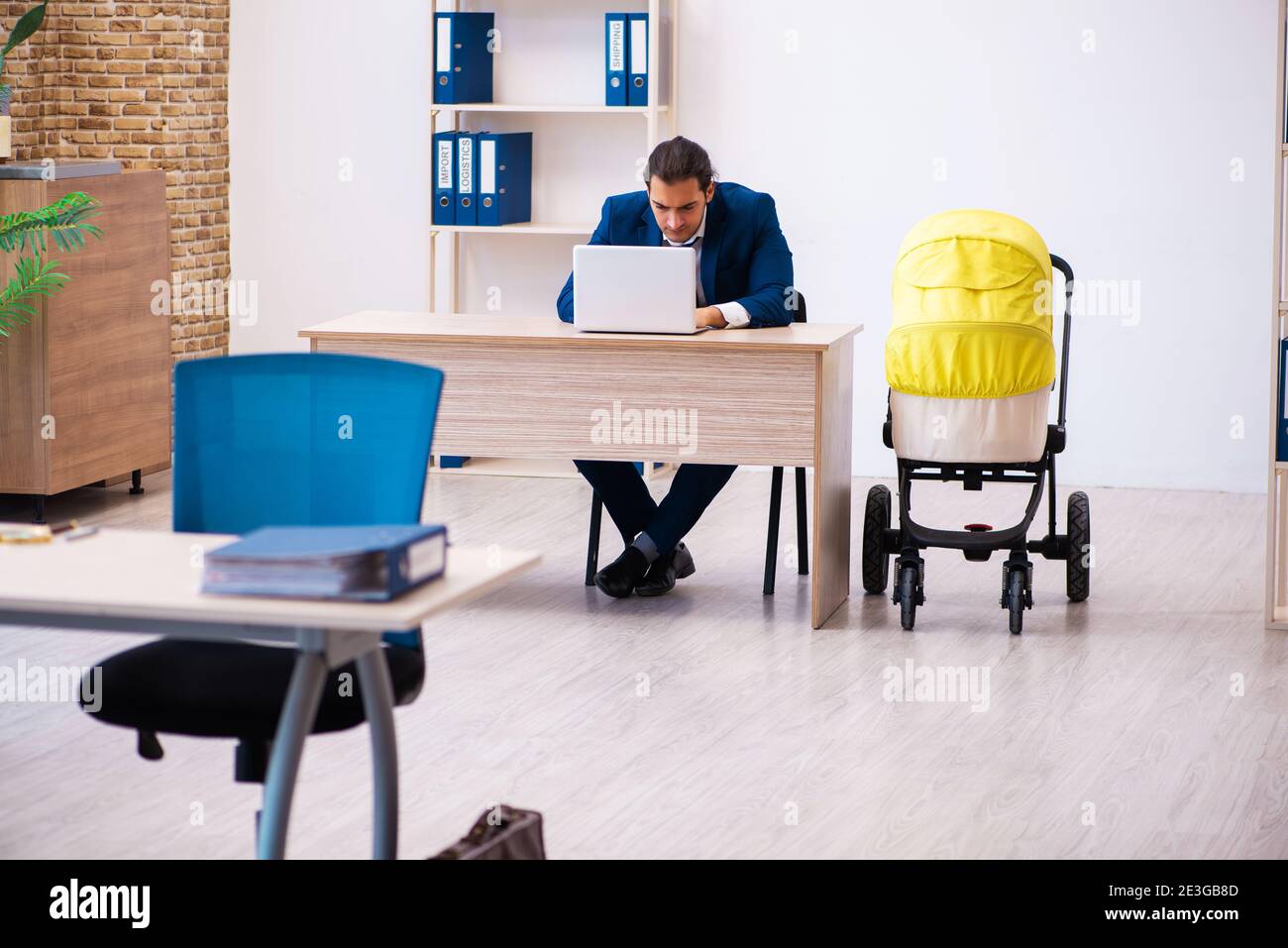 Young employee looking after kid at workplace Stock Photo - Alamy