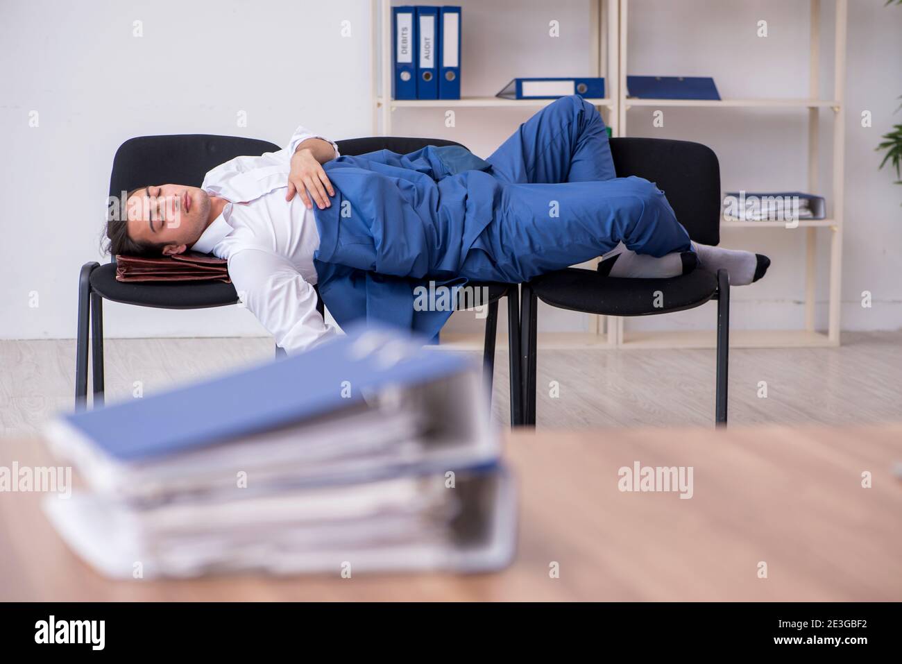 Young employee sleeping in the office on chairs Stock Photo - Alamy