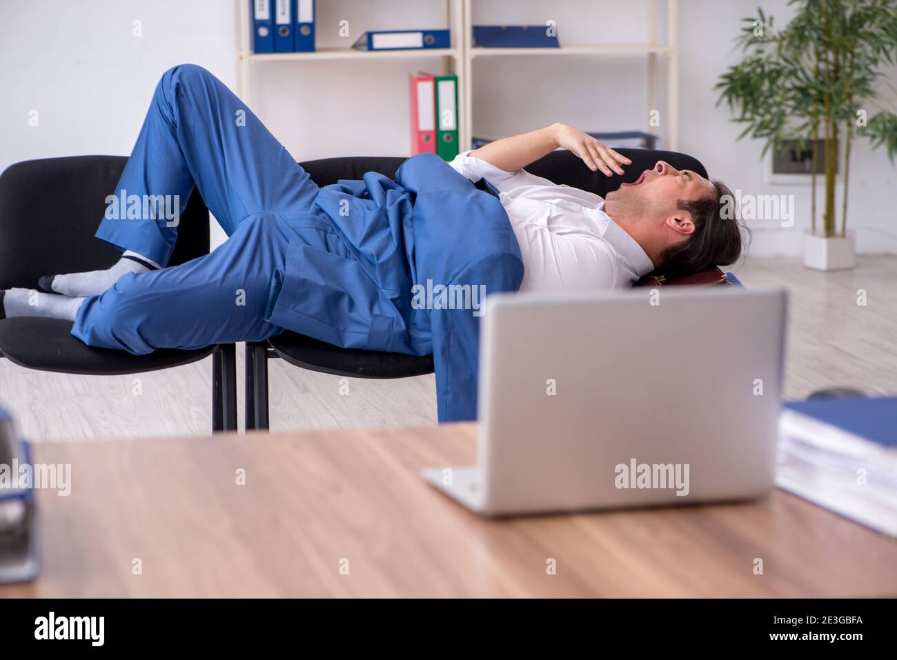 Young employee sleeping in the office on chairs Stock Photo - Alamy
