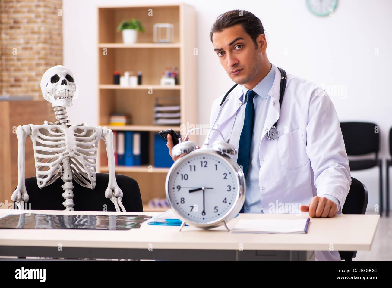 Young doctor and skeleton patient in time management concept Stock ...