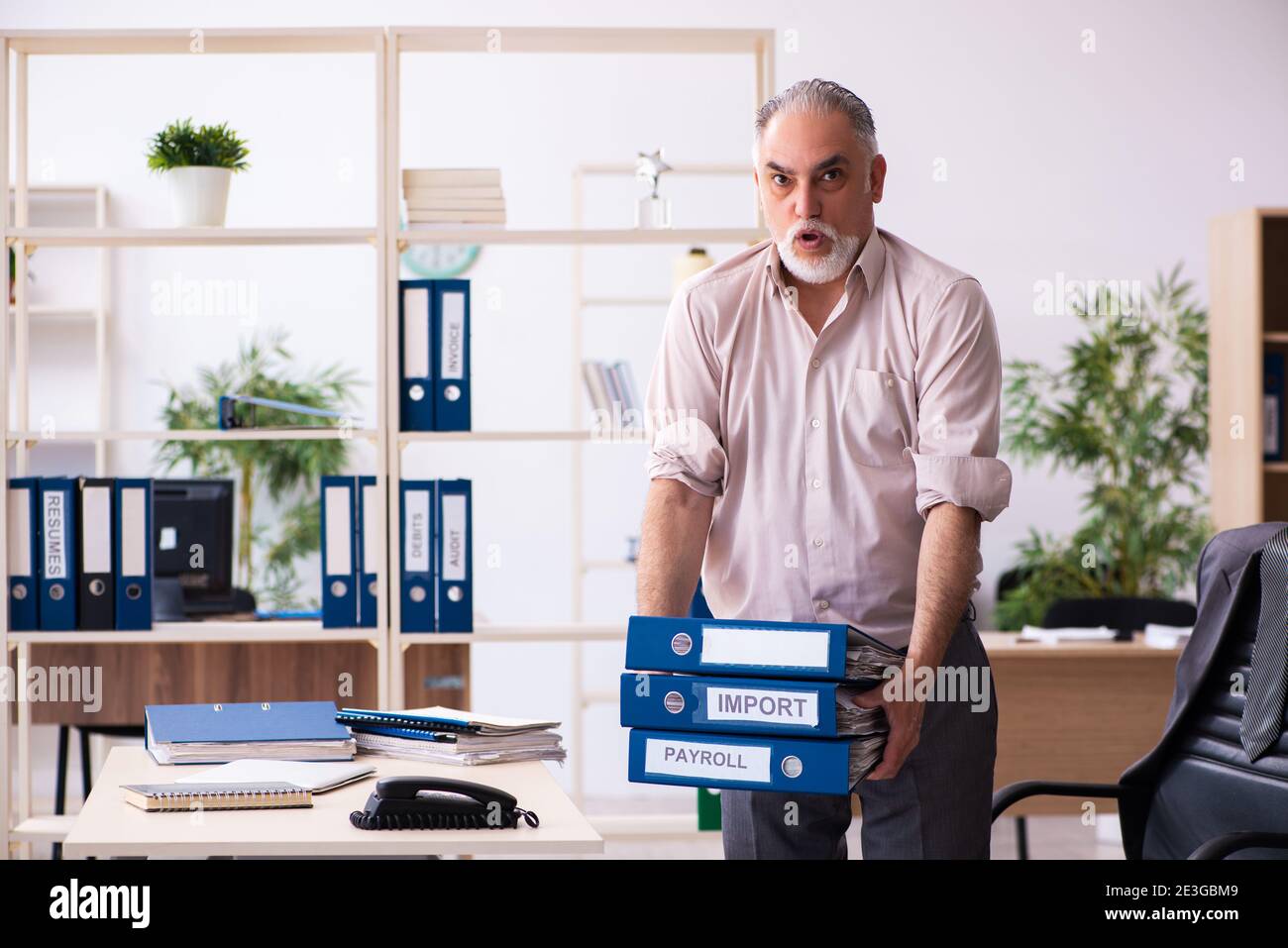 Senior male employee doing physical exercises at workplace Stock Photo ...