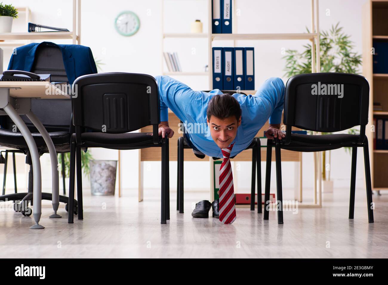 Young businessman doing sport exercises at workplace Stock Photo - Alamy