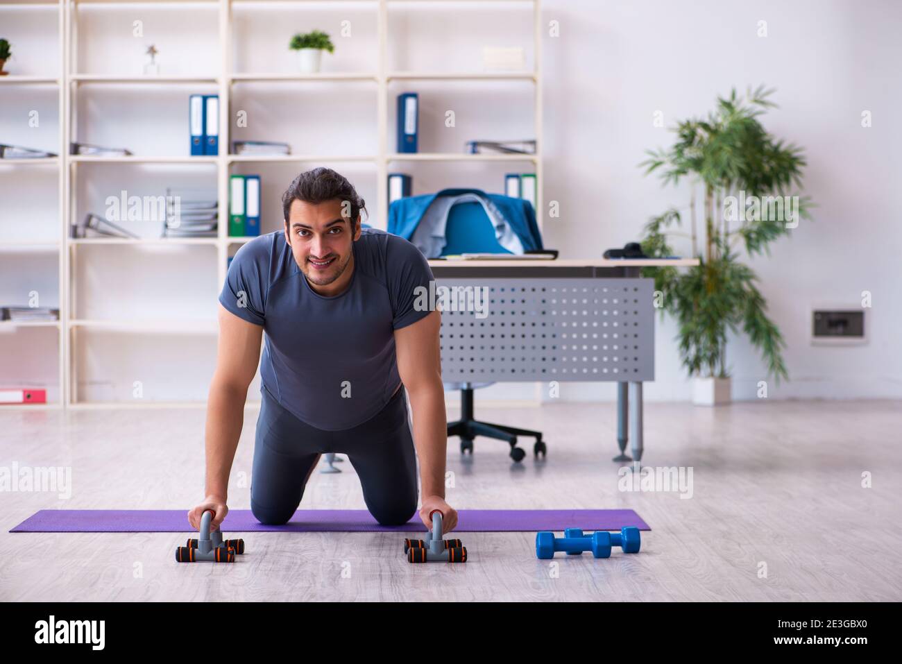 Young male employee doing sport exercises in the office Stock Photo - Alamy