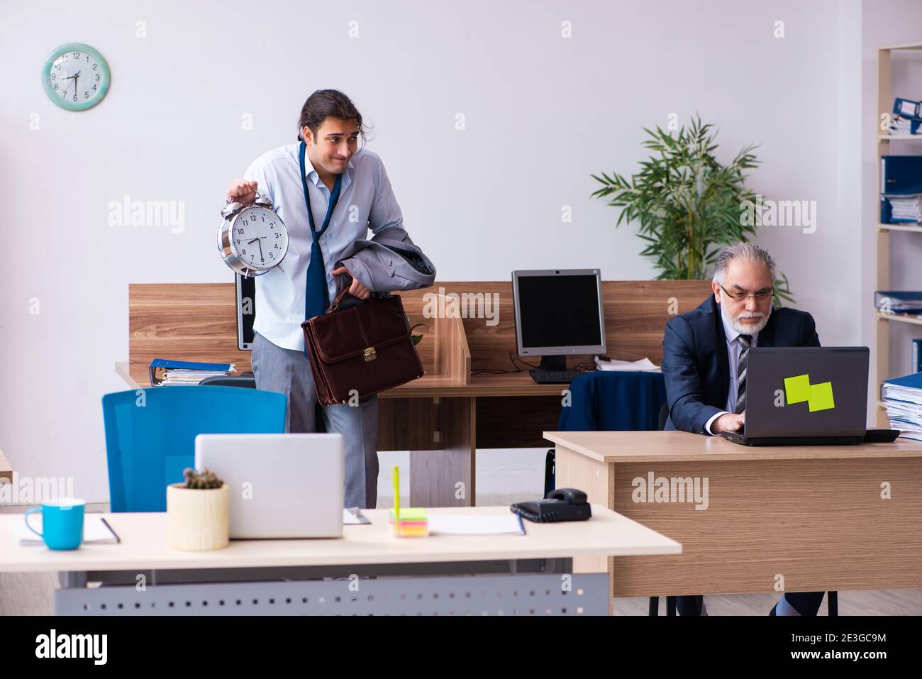 Old boss and young male employee in time management concept Stock Photo ...