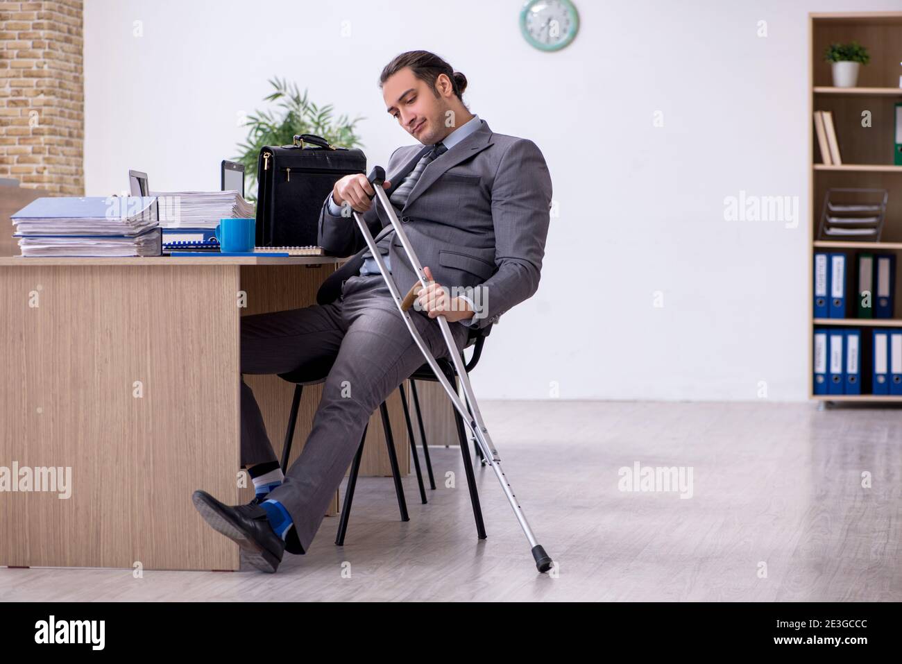 Young leg injured employee working in the office Stock Photo - Alamy