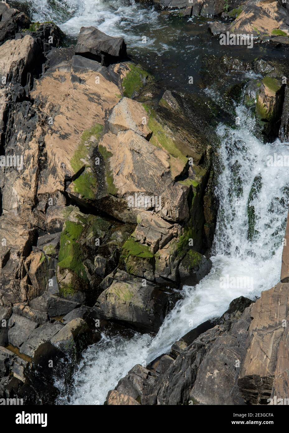 Flat light image of waterfall curving through the frame and moss on the ...