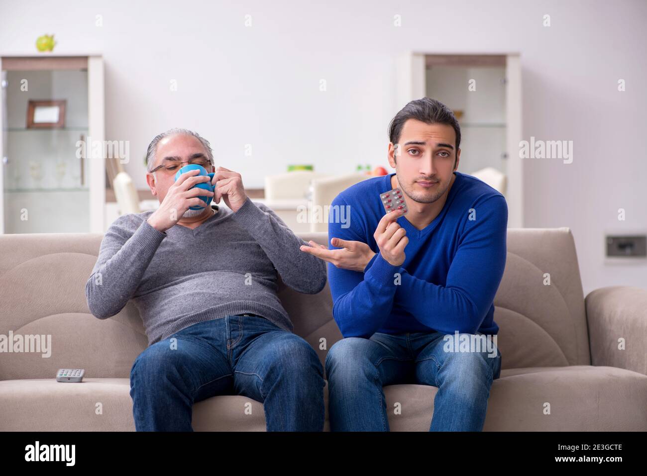Young man looking after his sick father at home Stock Photo - Alamy