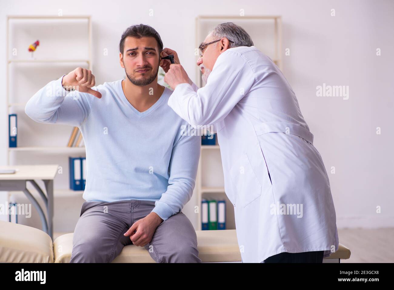 Sick man visiting old doctor otolaryngologist Stock Photo - Alamy