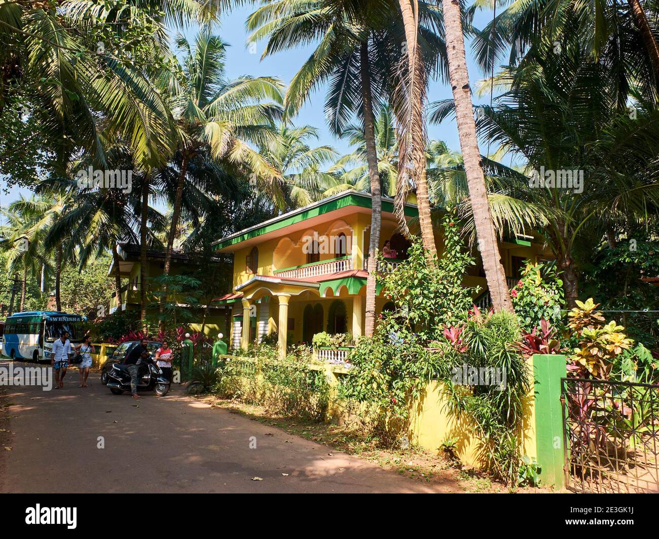 Colorful mansion in colonial style, palm trees and people on the street ...