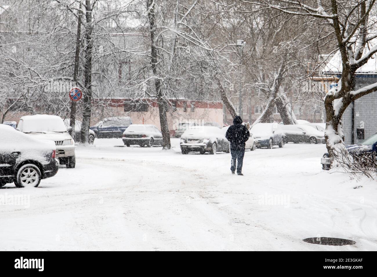 Snowfall and frost in urban environments. Man, cars and buildings are ...
