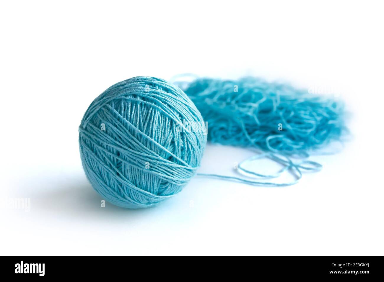 A ball of blue fine cotton yarn in the process of winding, isolated on ...