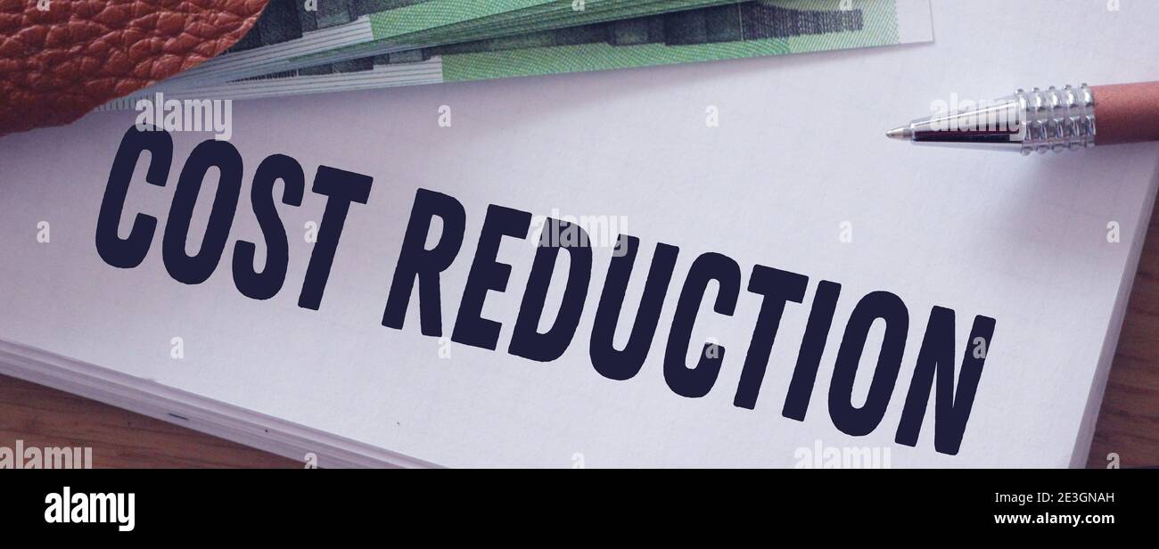 Cost Reductions words on copybook page, 100 Euro bills. Production or ...