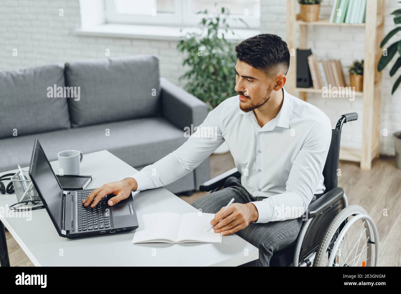 Positive disabled young man in wheelchair working in office Stock Photo ...