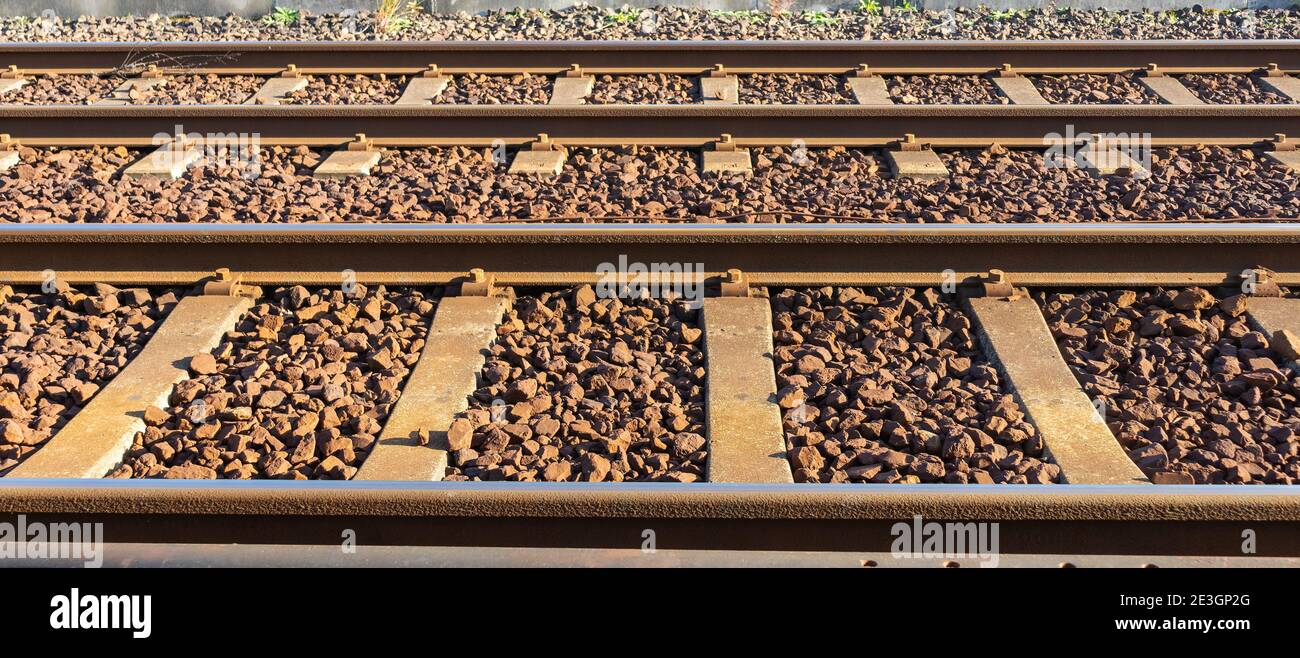 4 railway tracks, resting on stone track ballasts. with rust colored ...