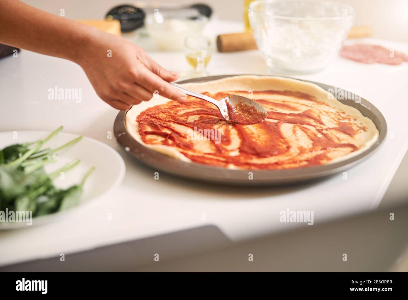 Covering the pizza base with tomato sauce Stock Photo - Alamy