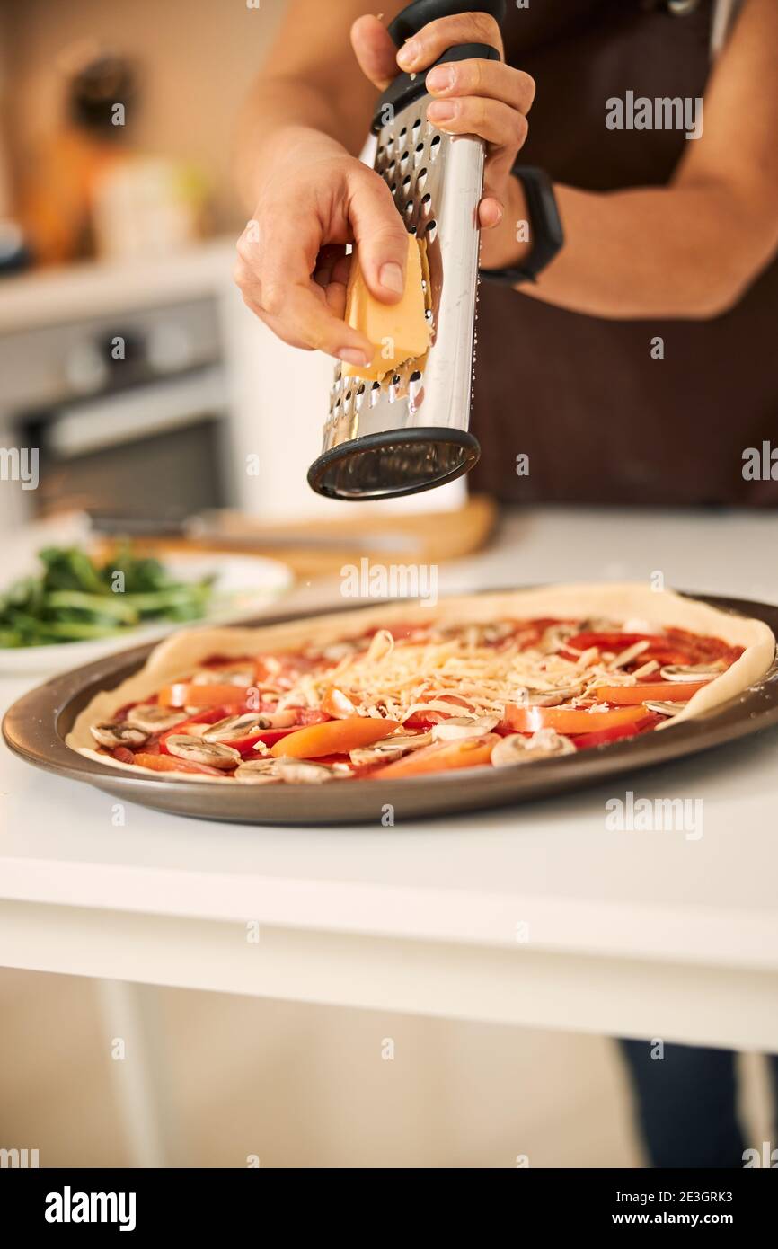 Grating cheese while cooking homemade pizza at home Stock Photo - Alamy
