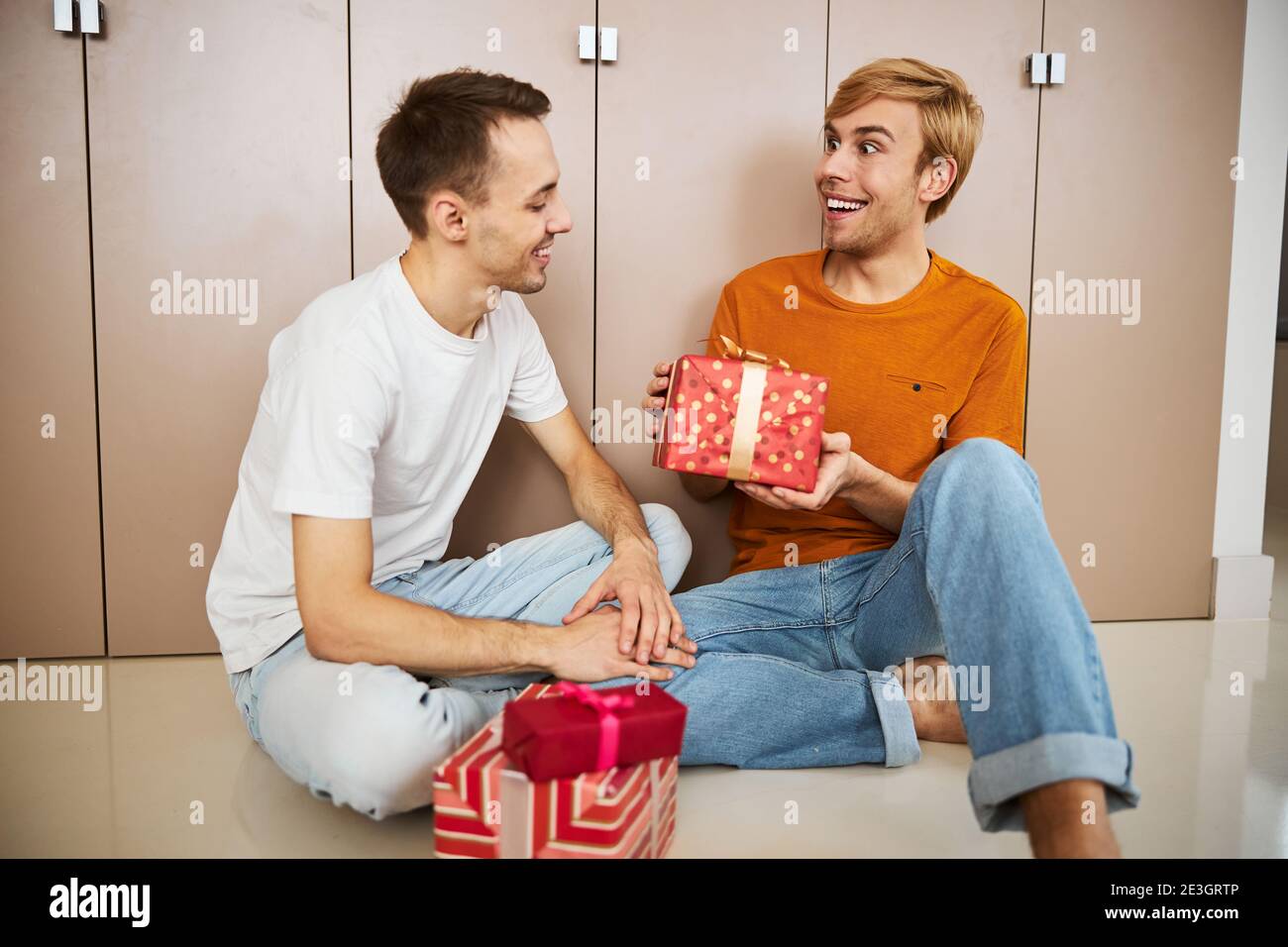Joyful young man giving present to his boyfriend at home Stock Photo ...