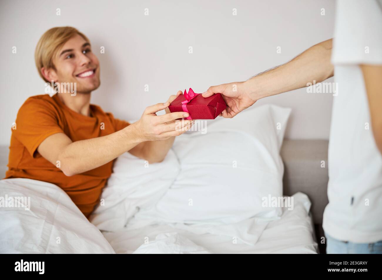 Cheerful young man accepting gift box from boyfriend Stock Photo - Alamy
