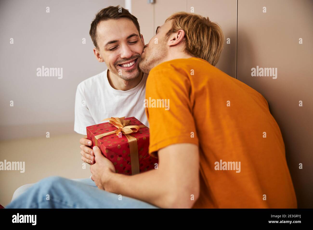 Happy young man accepting present from loving boyfriend Stock Photo - Alamy