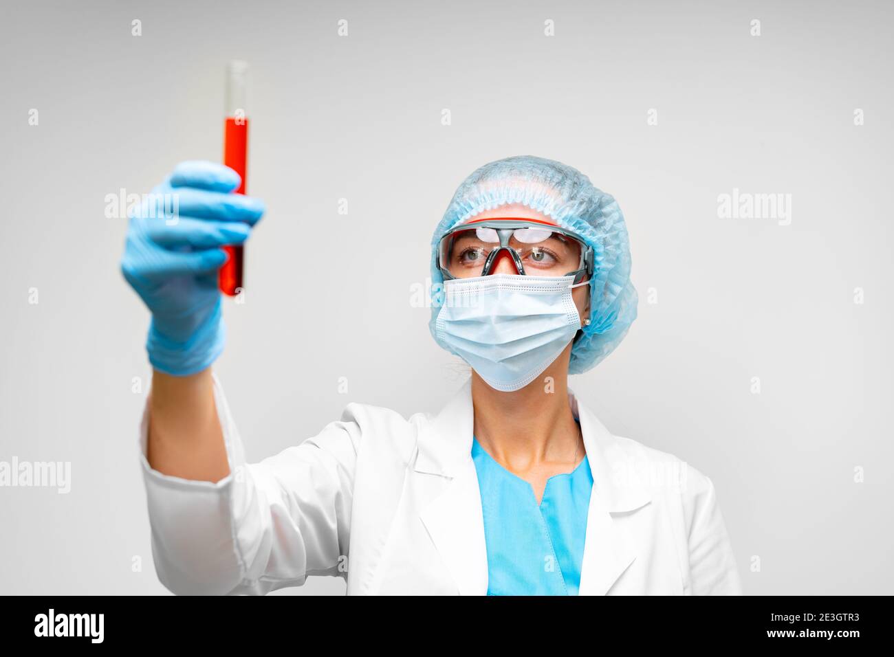 Woman scientist holding laboratory flask with chemical liquid, gray ...