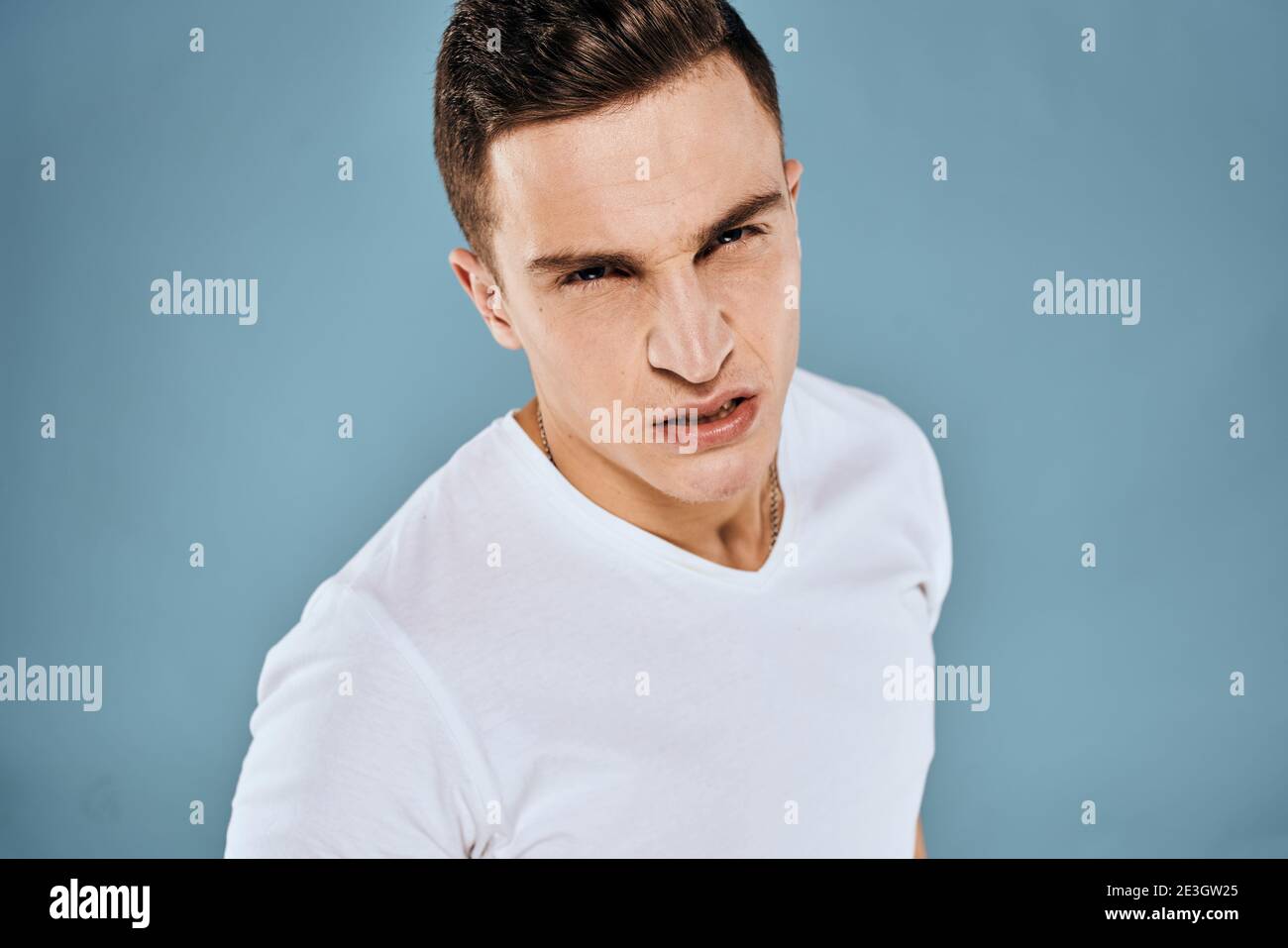 emotional displeased man cropped view white t-shirt blue background ...