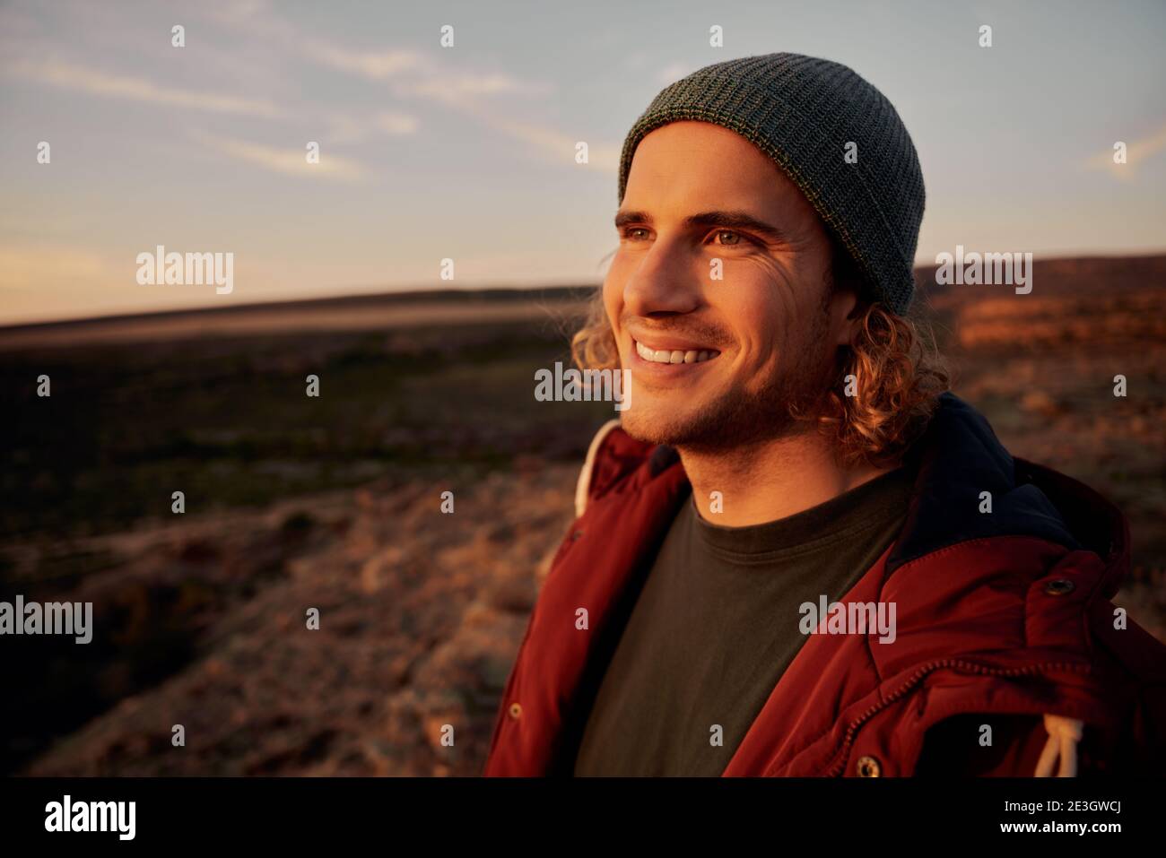 Portrait of happy male wearing cap smiling with sunrays falling on face ...