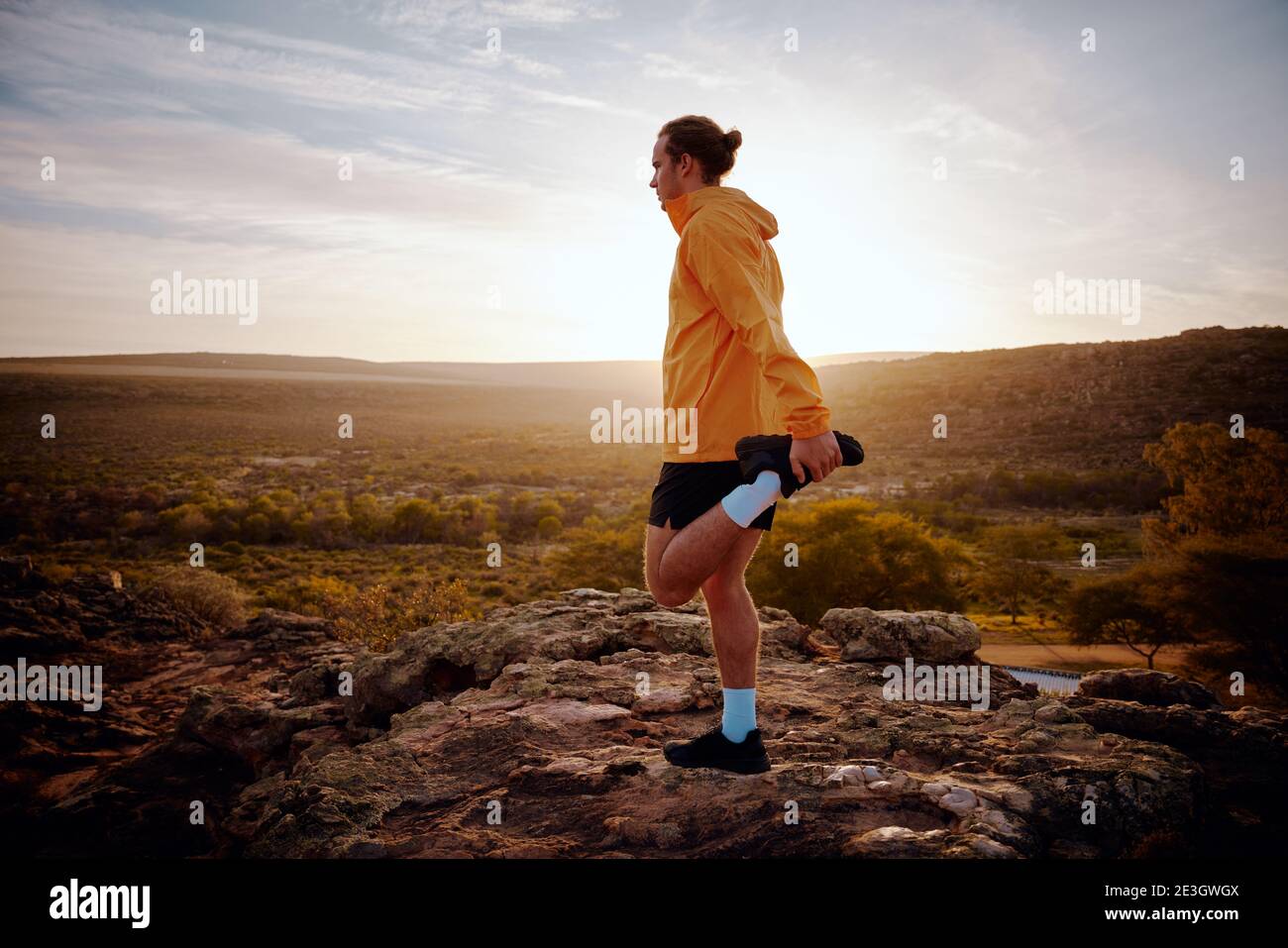 Male athlete doing leg stretching exercise preparing for run in nature ...