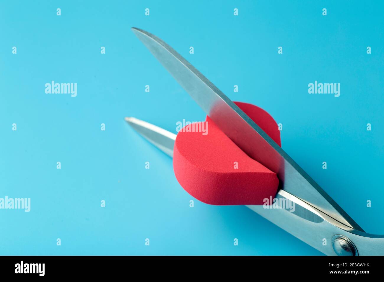 Broken heart cut with scissors on a colored background. Unhappy love ...