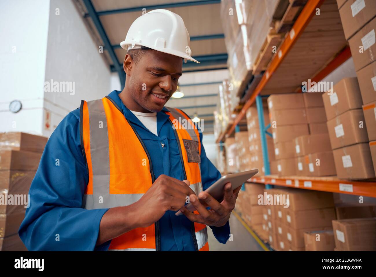 Happy african industrial staff using digital tablet in large warehouse ...