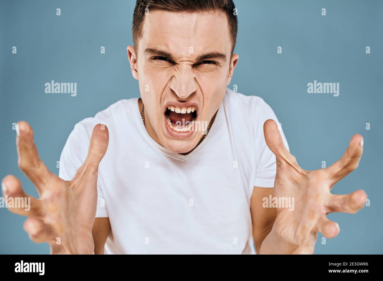 emotional displeased man cropped view white t-shirt blue background ...