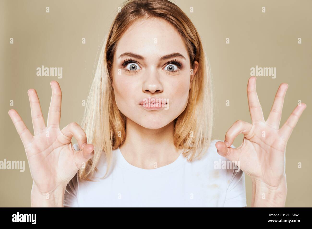 Cheerful blonde woman in a white T-shirt gestures with her hand emotions beige background Stock ...