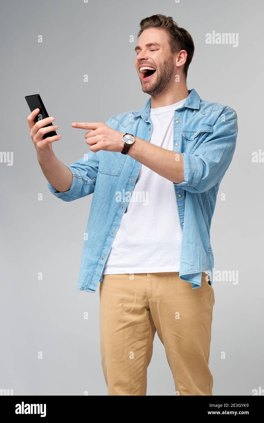 Smiling young man wearing jeans shirt taking selfie photo on smartphone ...
