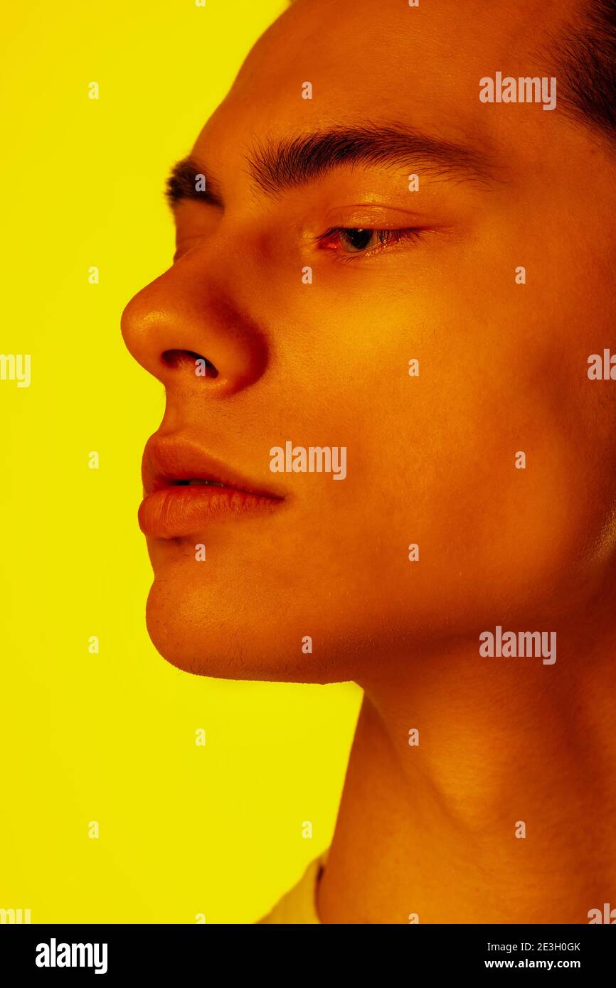 Cheeks. Handsome caucasian man's portrait isolated on orange studio ...