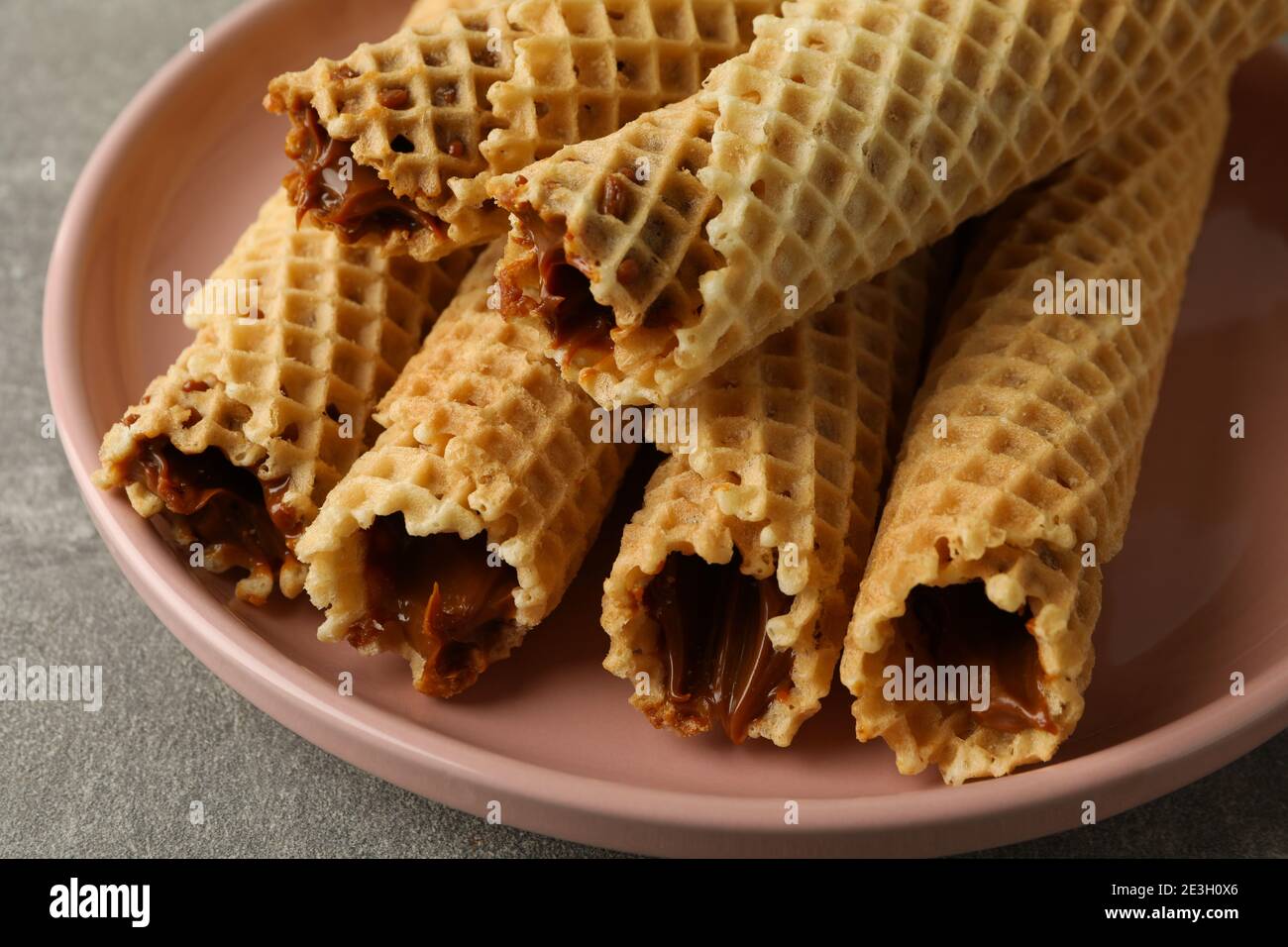 Plate with wafer rolls with condensed milk on gray background Stock ...