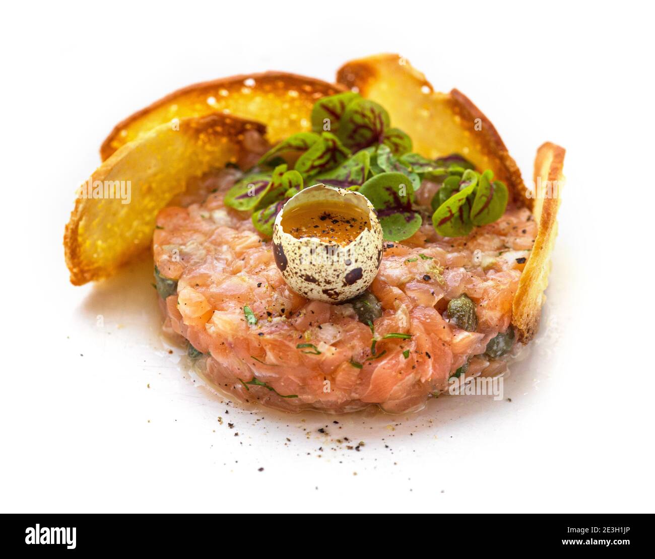 plate of salmon tartare with raw egg and toasted bread slices close up ...