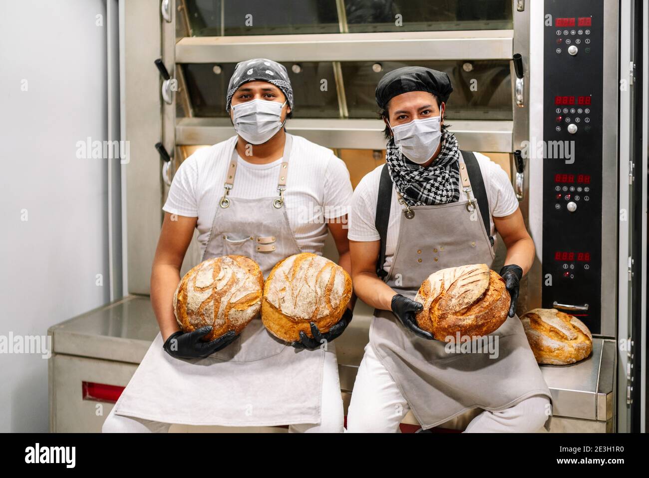 two happy latino bakers showing how they made a loaf of wheat bread in ...